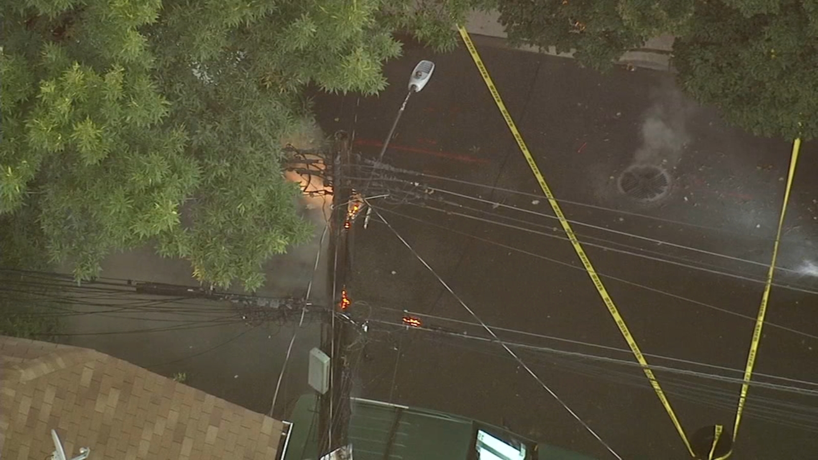 Firefighters douse utility pole fire as smoke pours from manhole in ...
